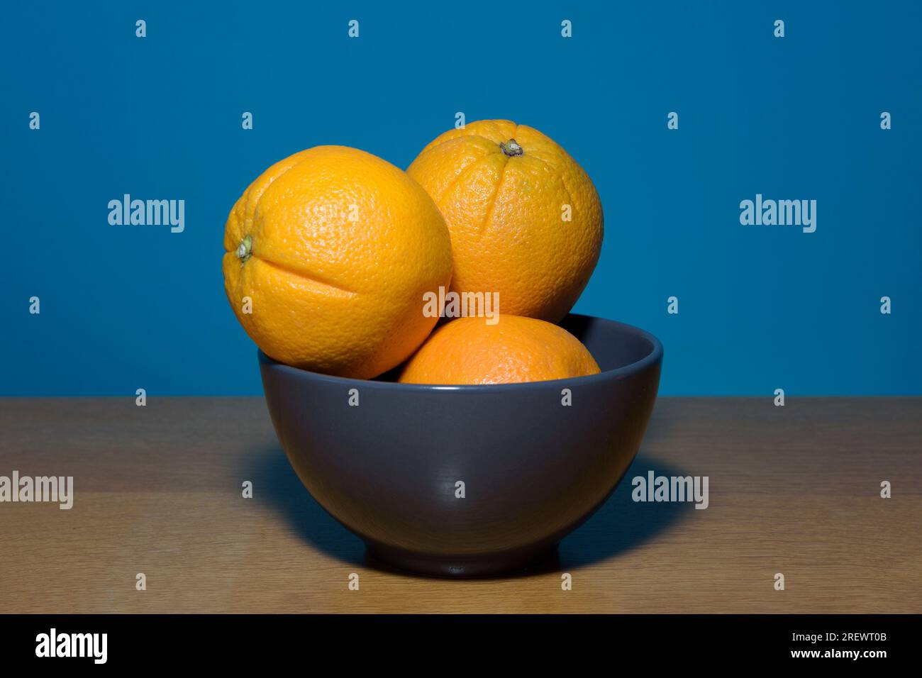 Natural oranges. Three oranges in a gray cup on a blue background ...