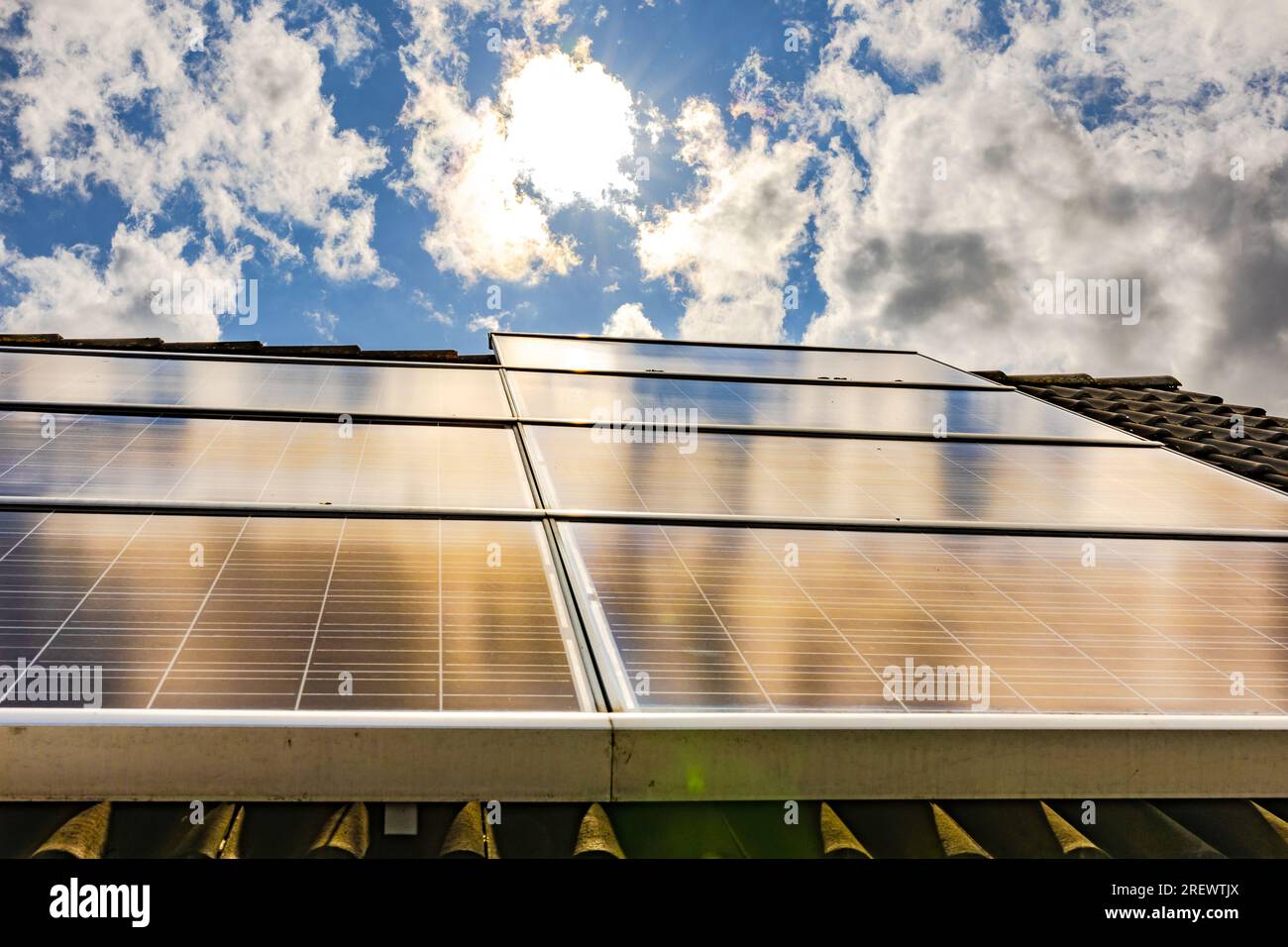 Solar panels on a house roof in evening mood and back light with clouds ...