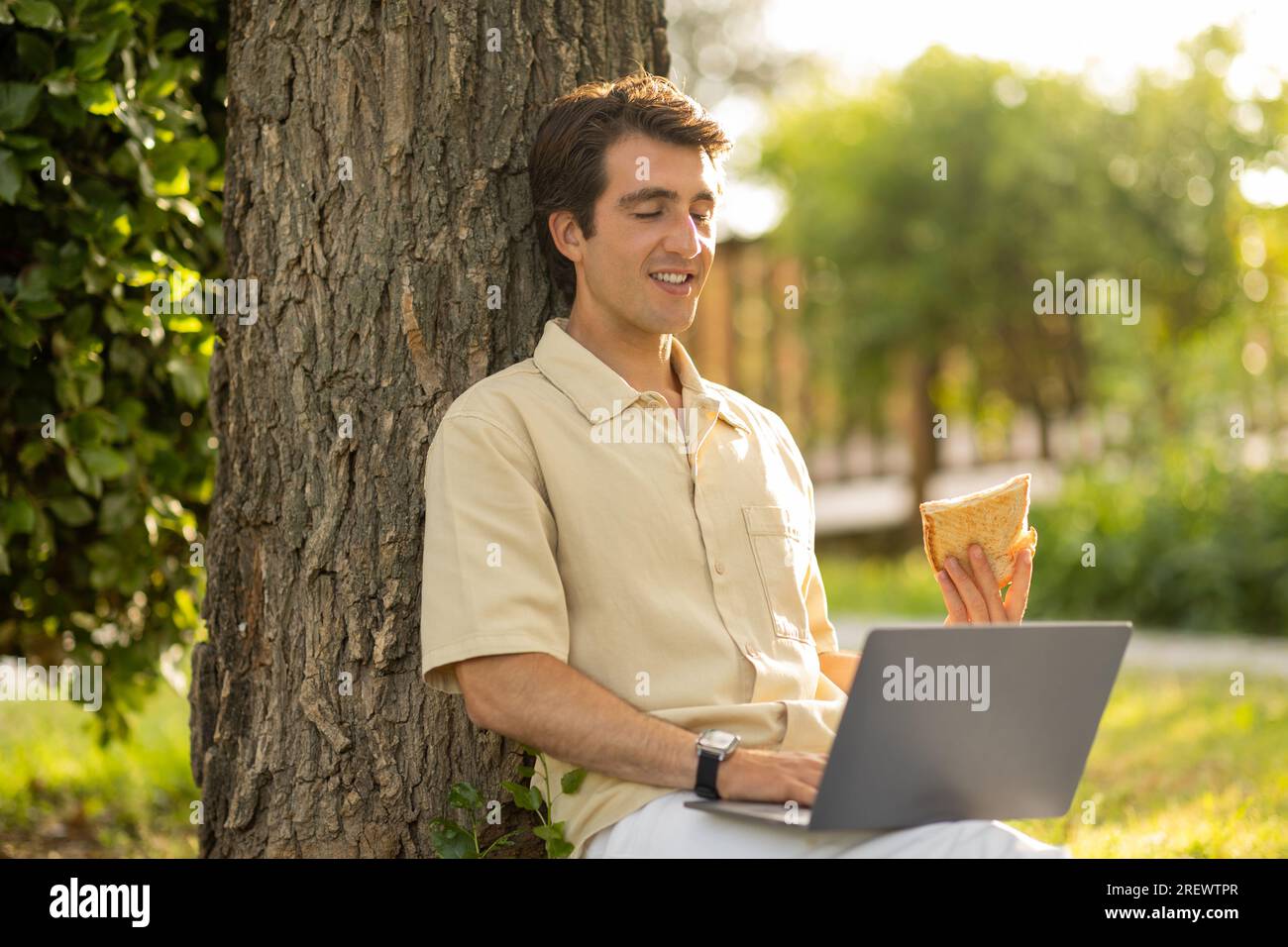 Cheerful millennial guy watching movie while relaxing at garden Stock ...