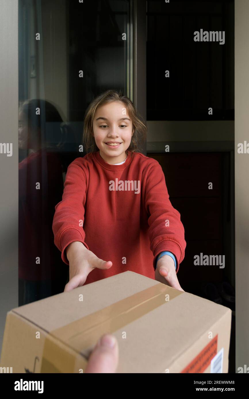 A teenage girl happily accepts a parcel from the postman. Life style ...