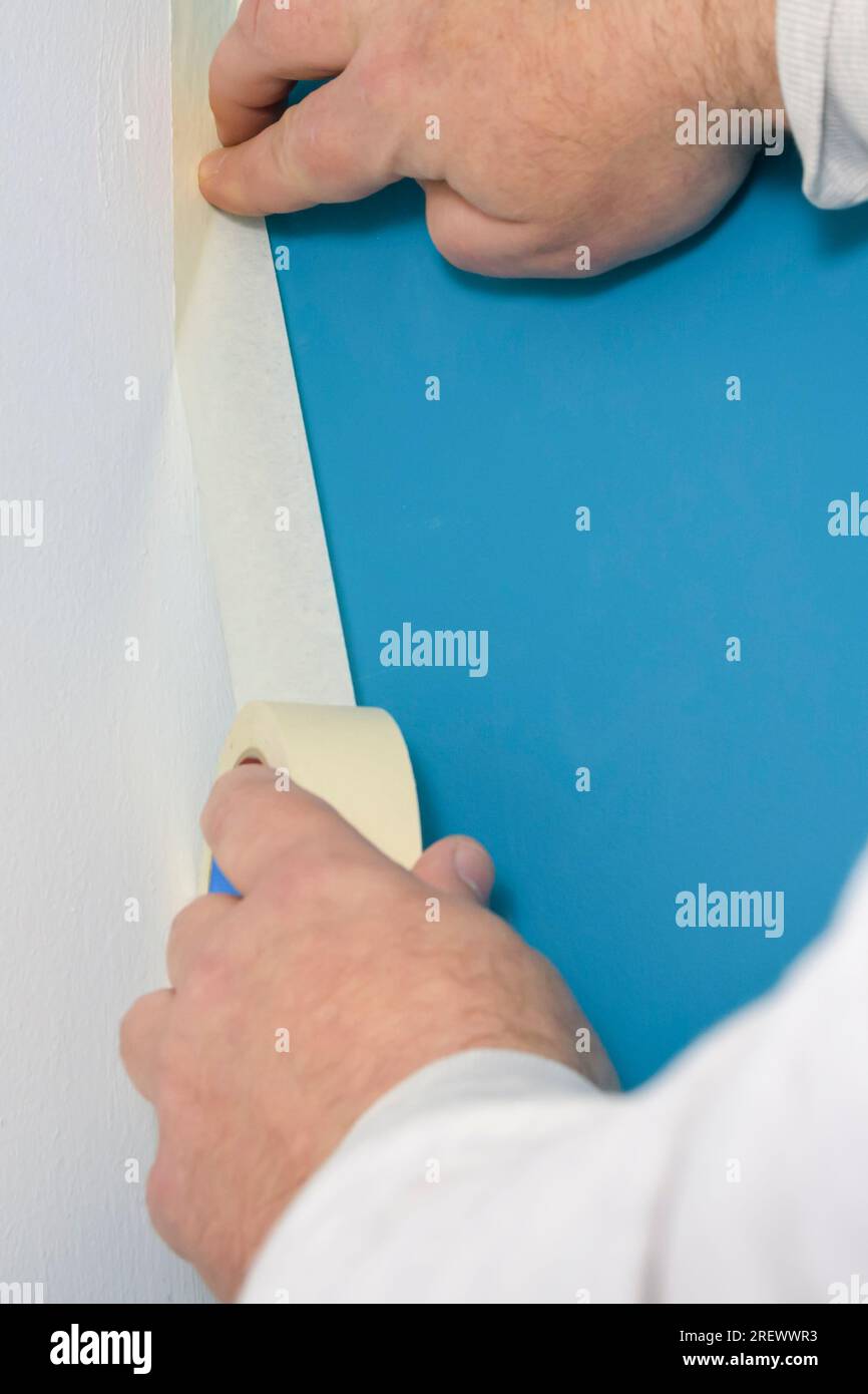 Applying masking tape to be painted. Vertical. Border of white and blue ...