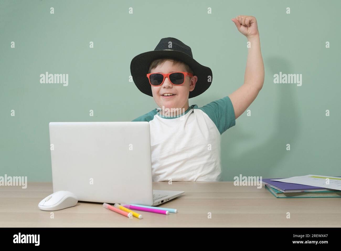 School vacation. A teenager at a desk and a computer rejoices at the ...