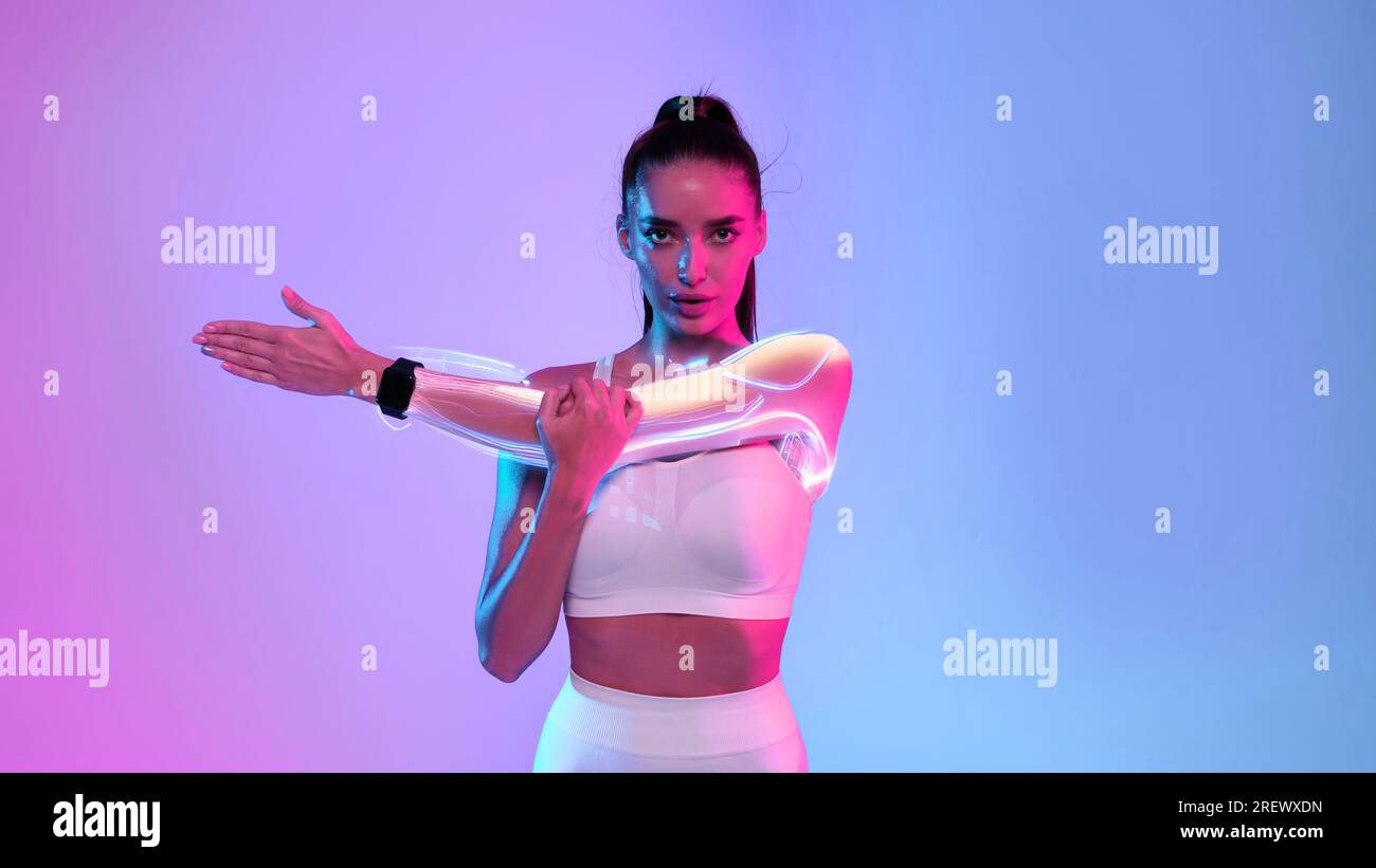 Fit lady stretching arms wearing fitness watch exercising, studio shot ...
