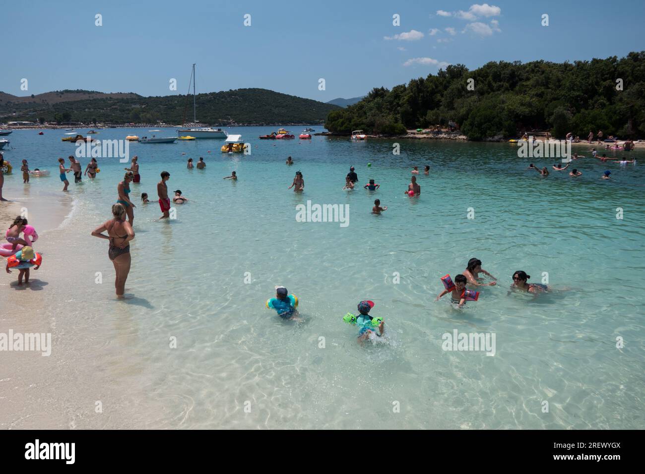 View of crowded beach in Ksamil, Albania with people swimming and ...