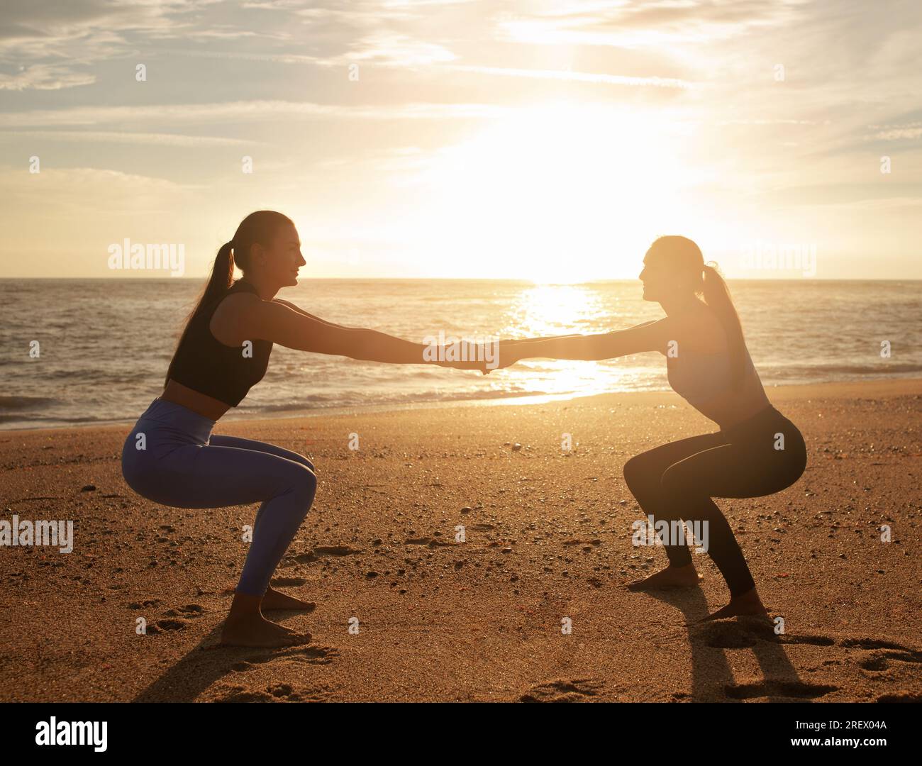Smiling millennial caucasian twins sisters women squats, do leg ...