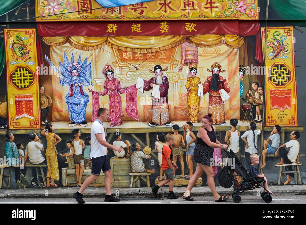 A Caucasian family passes a mural by Singaporean artist Yip Yew Chong ...