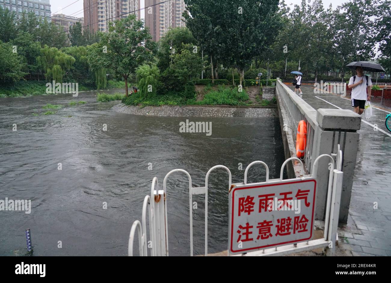 Beijing, China. 30th July, 2023. People walk amid the rain in Beijing ...