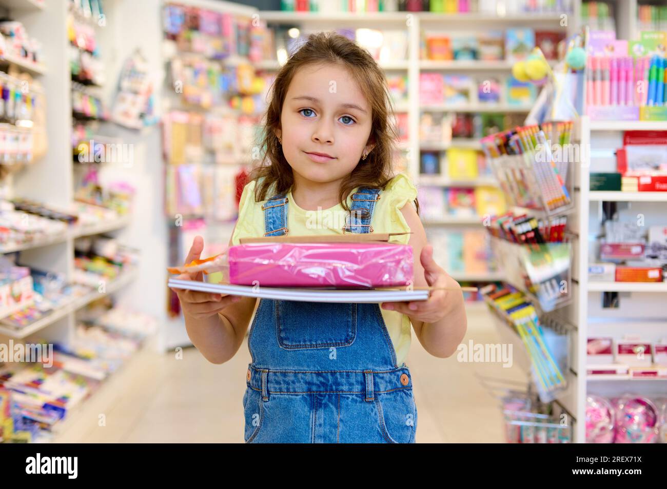 Confident portrait of Caucasian little kid girl holding school supplies ...