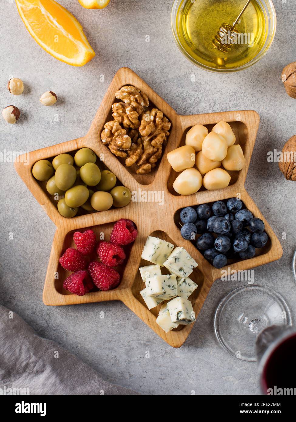 Wine plate. Pieces of cheese, nuts in a wooden plate with glasses of ...