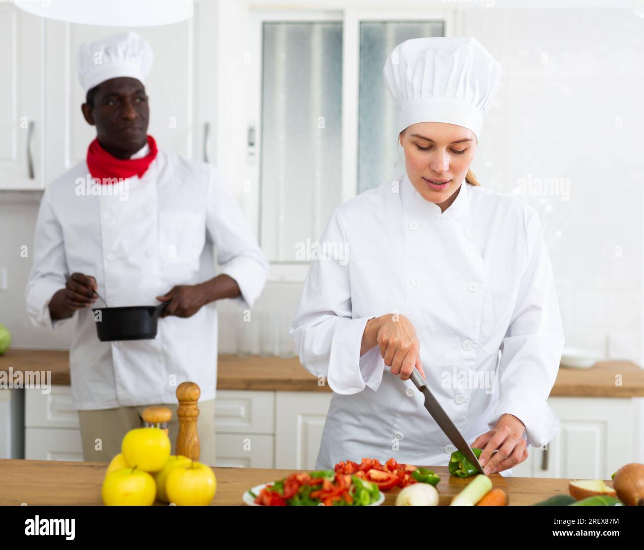 Two female and male cooks wearing uniform working on kitchen Stock ...