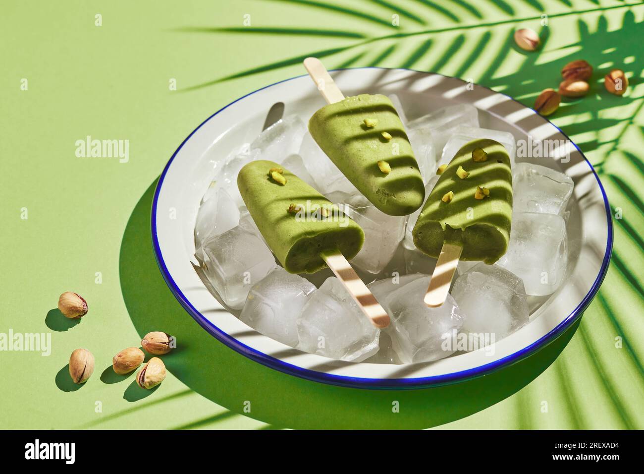 Frozen homemade pistachio popsicle in bowl of ice on green background ...