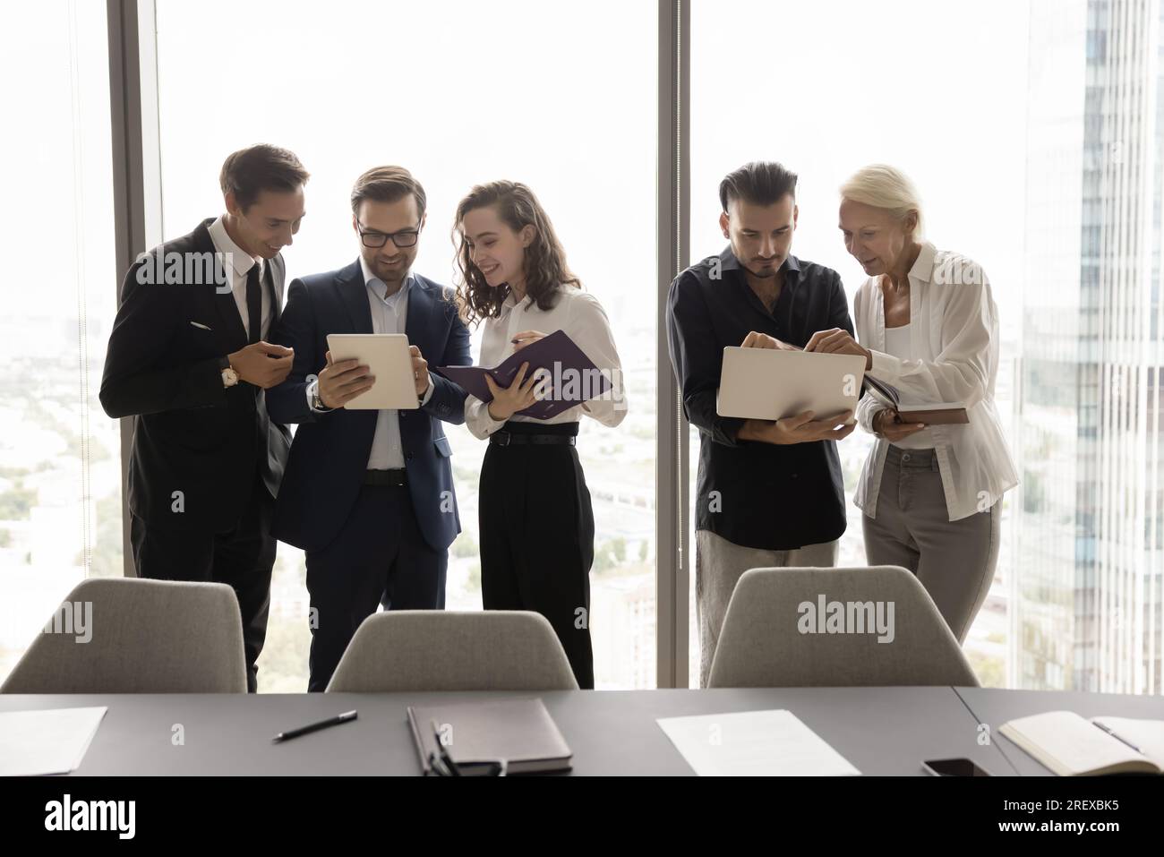 Two office business groups cooperating on tasks, using computer gadgets ...
