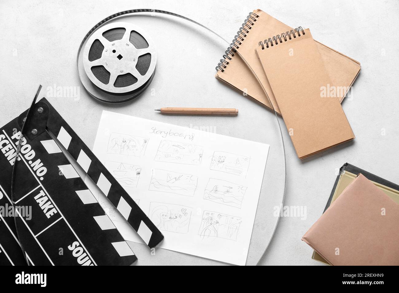 Movie clapper with storyboard, notebooks and film reel on light ...