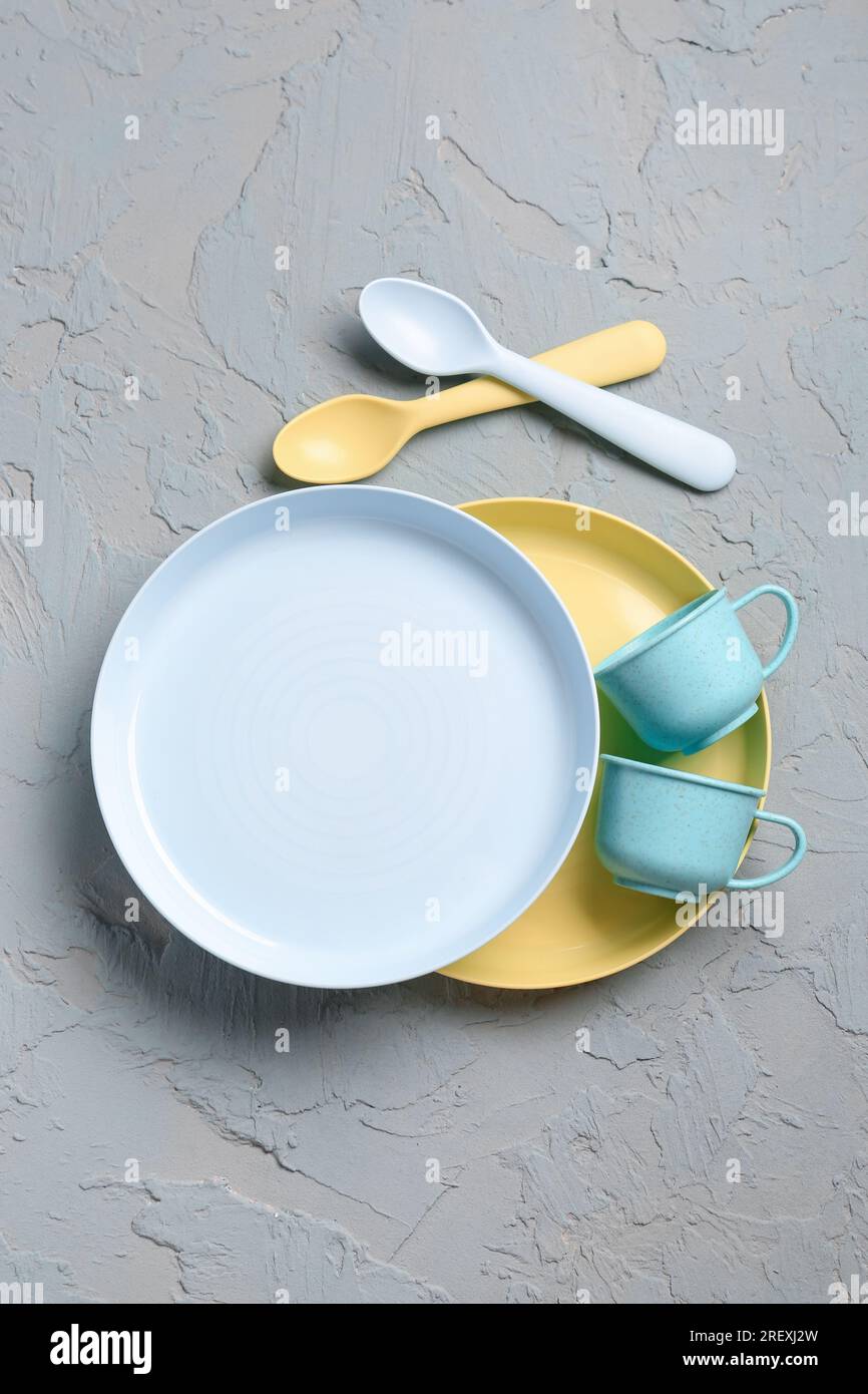 Cups with plates and spoons on grunge grey background Stock Photo - Alamy