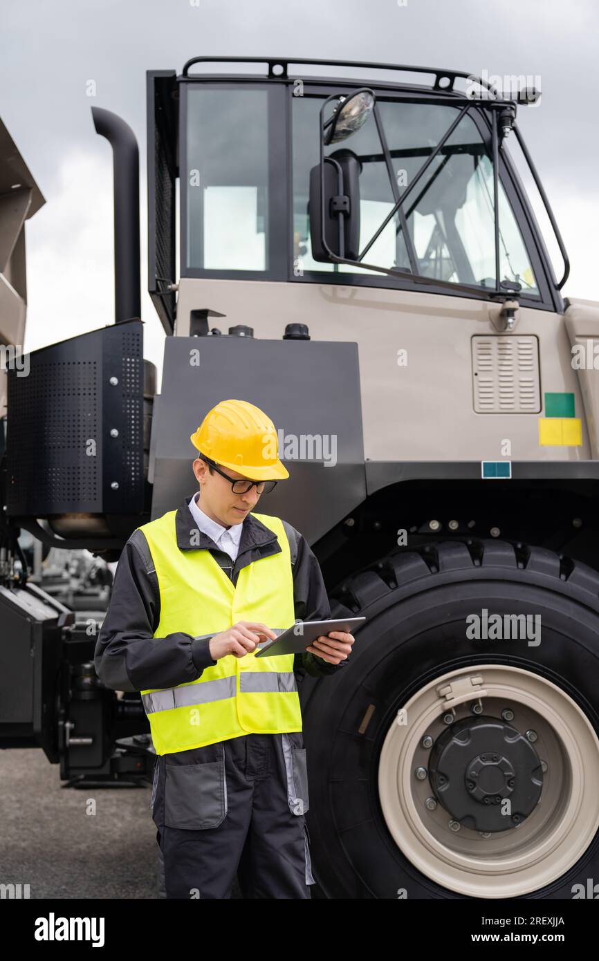 Engineer with tablet computer stands next to mining truck Stock Photo ...
