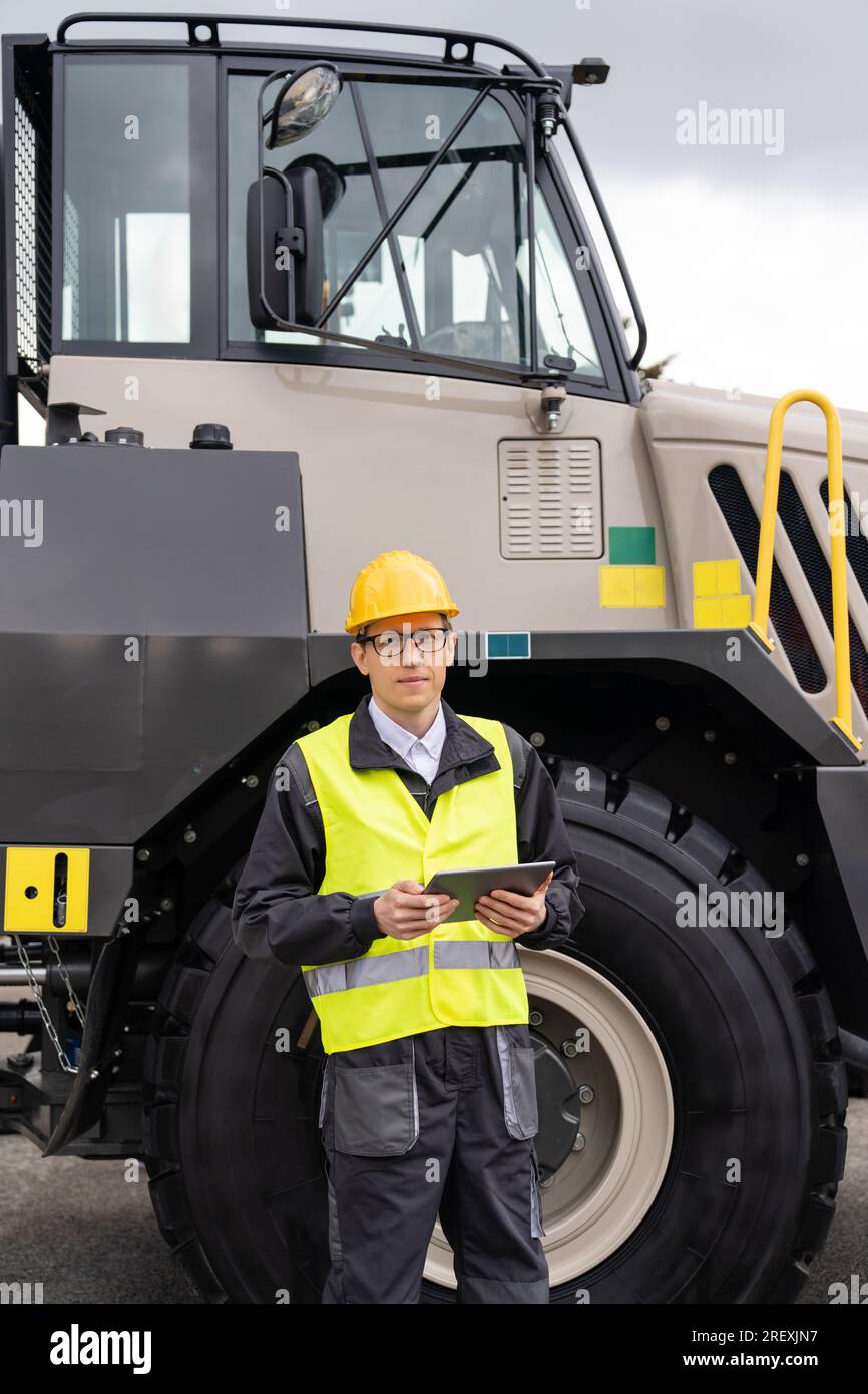 Engineer with tablet computer stands next to mining truck Stock Photo ...