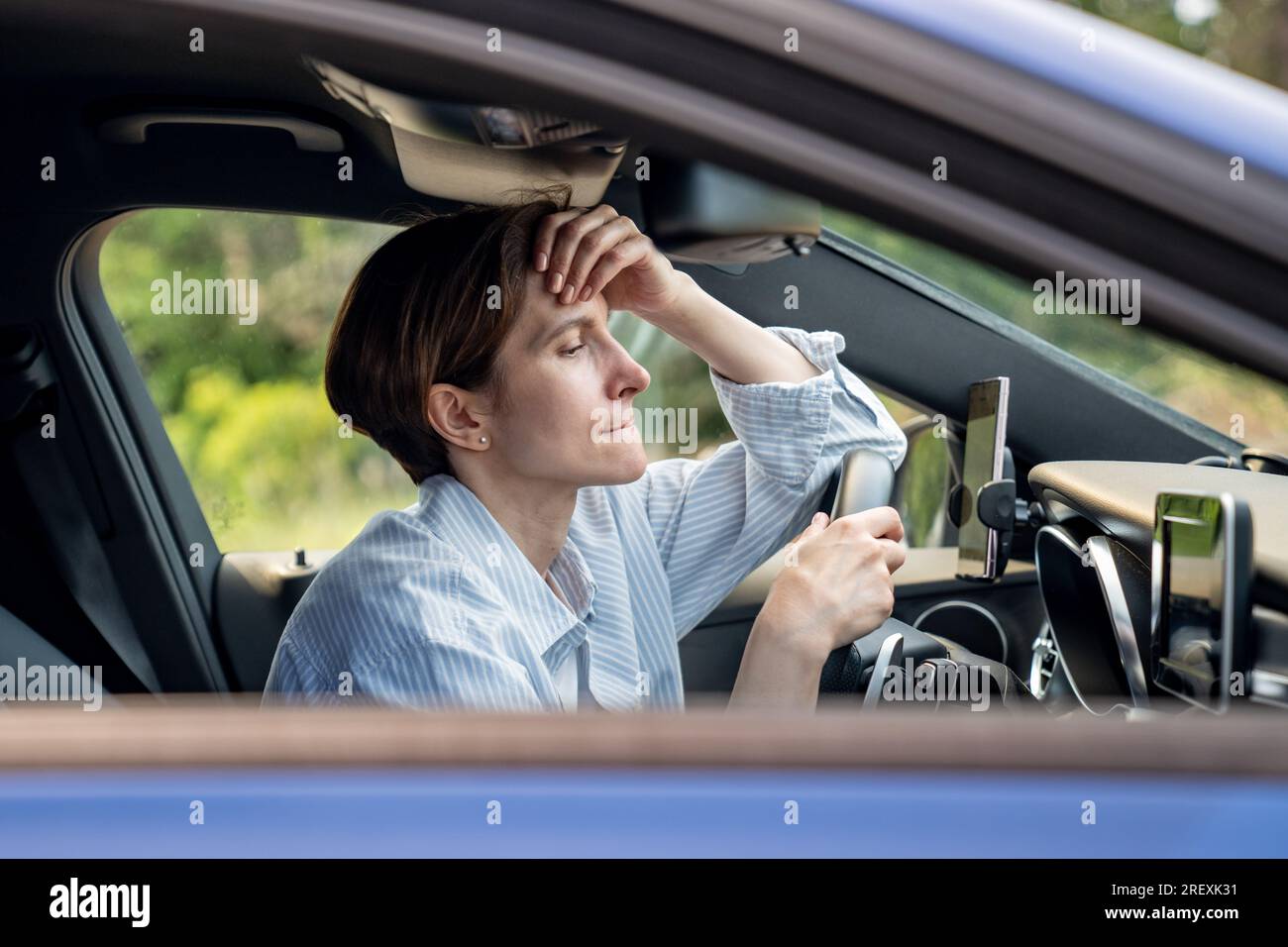 Stressed middle aged woman driving car having problems on road looking ...