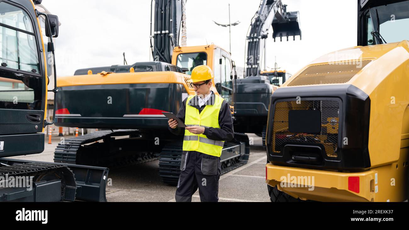 Engineer in a helmet with a digital tablet stands next to construction ...