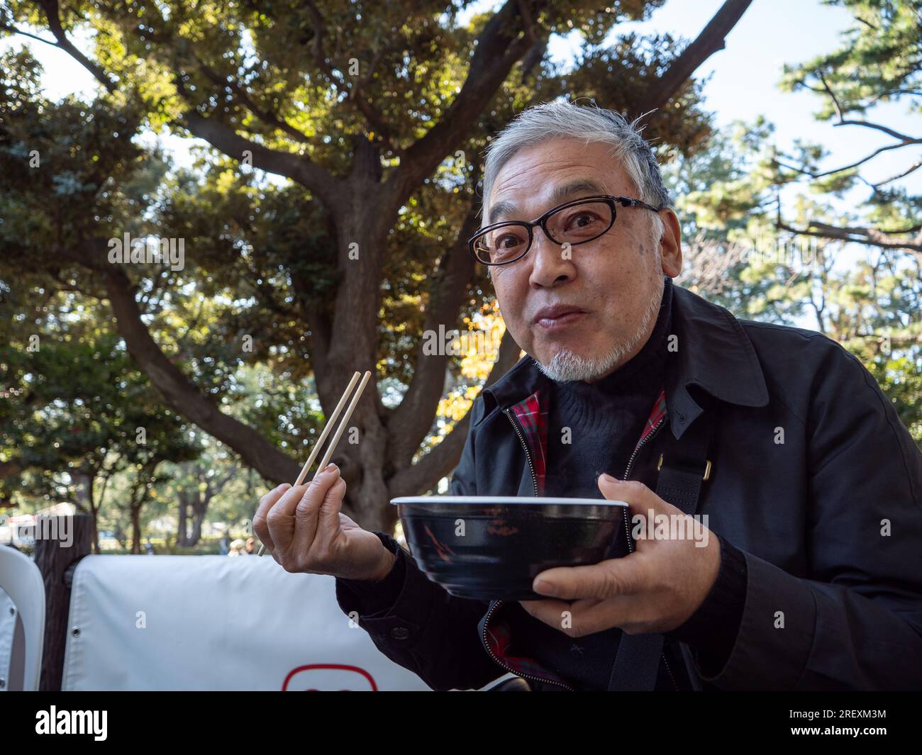 An older asian man eating noodles and soup with chopsticks Stock Photo ...