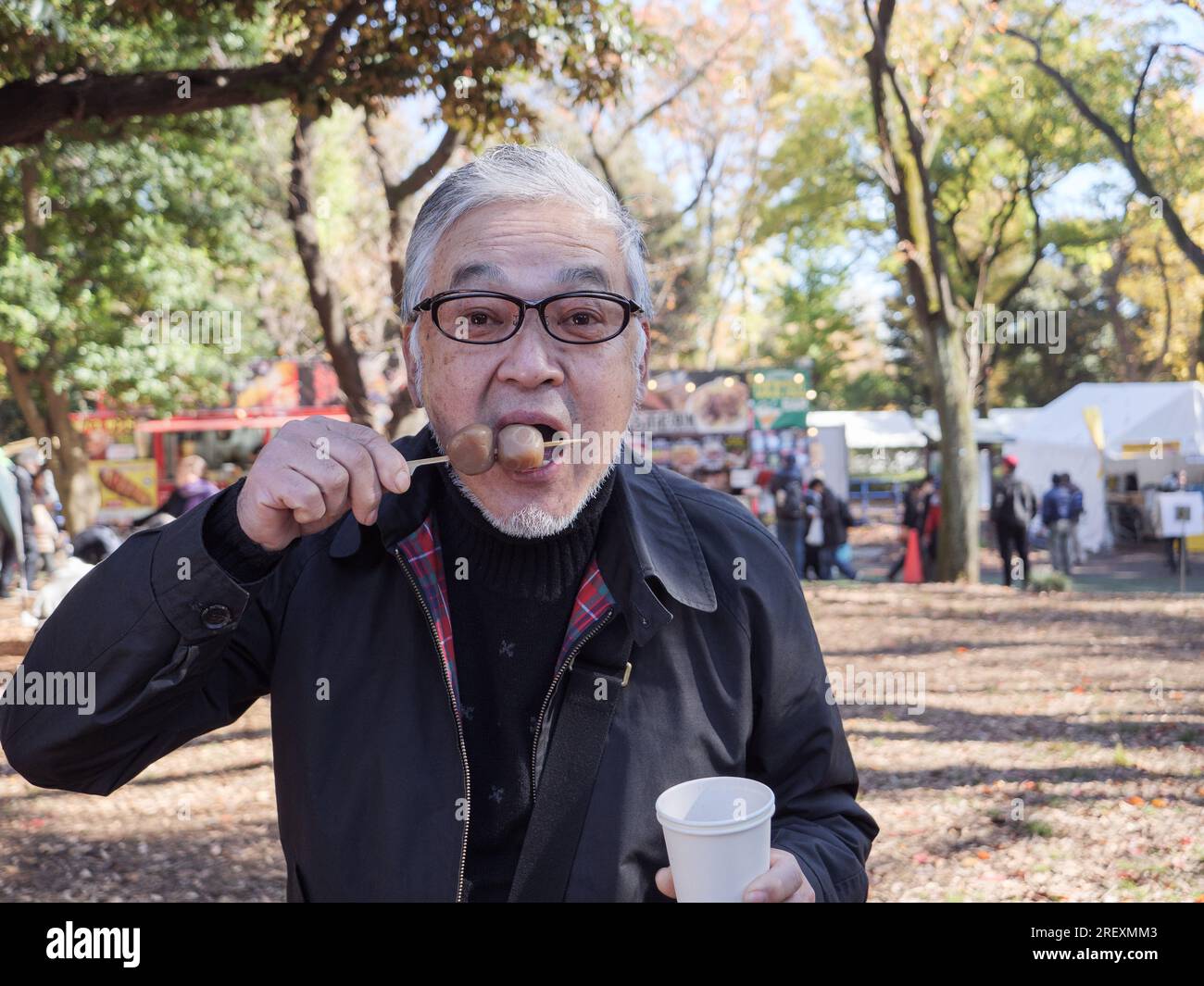 An older Japanese man eating dango and drinking coffee funnily Stock ...