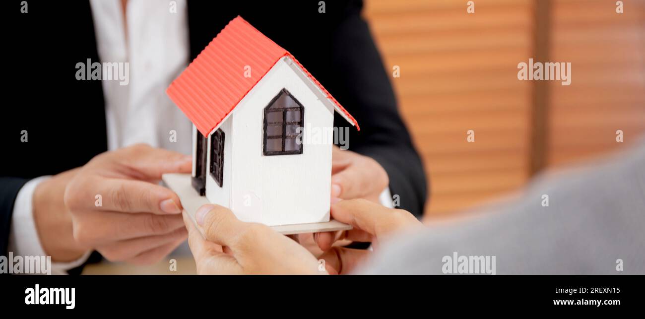 Closeup hands of young realtor man real estate giving house model to ...