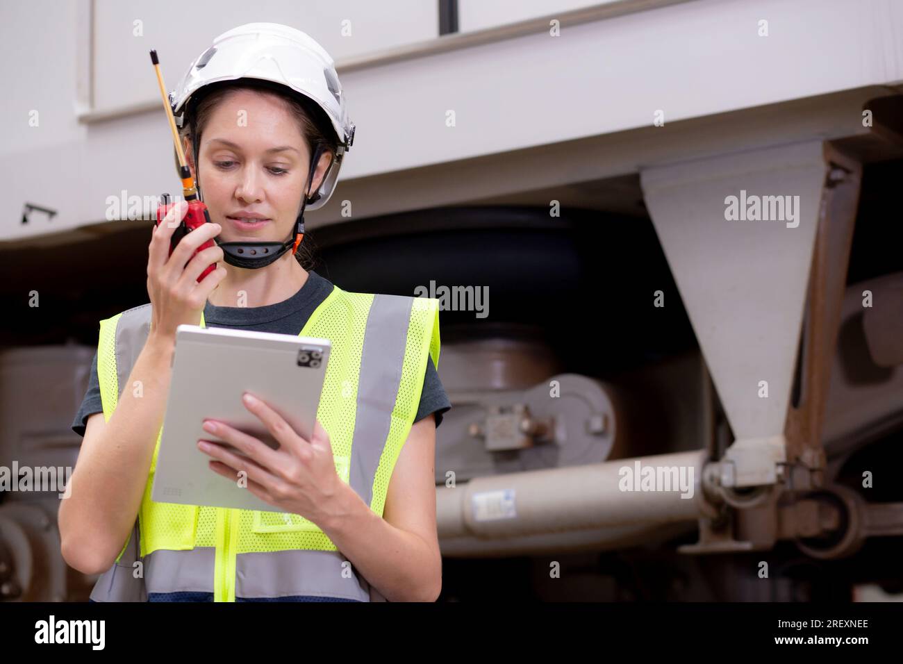 Young caucasian engineer woman using radio for command with worker ...