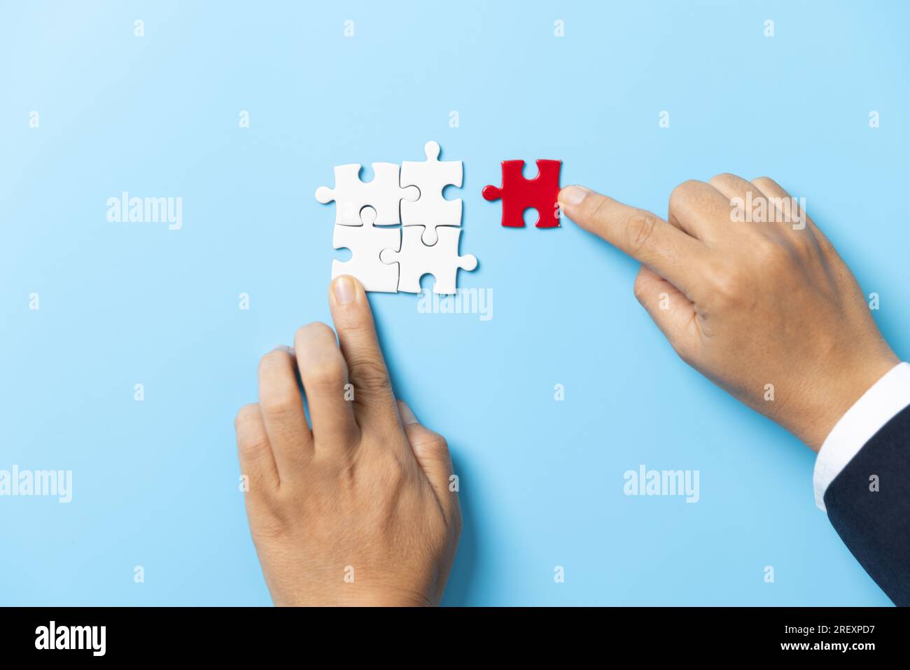 Two hands trying to connect couple puzzle piece on blue background ...