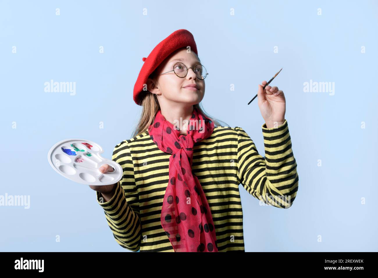 Girl with a palette of colors in a bright red beret and with a brush on ...