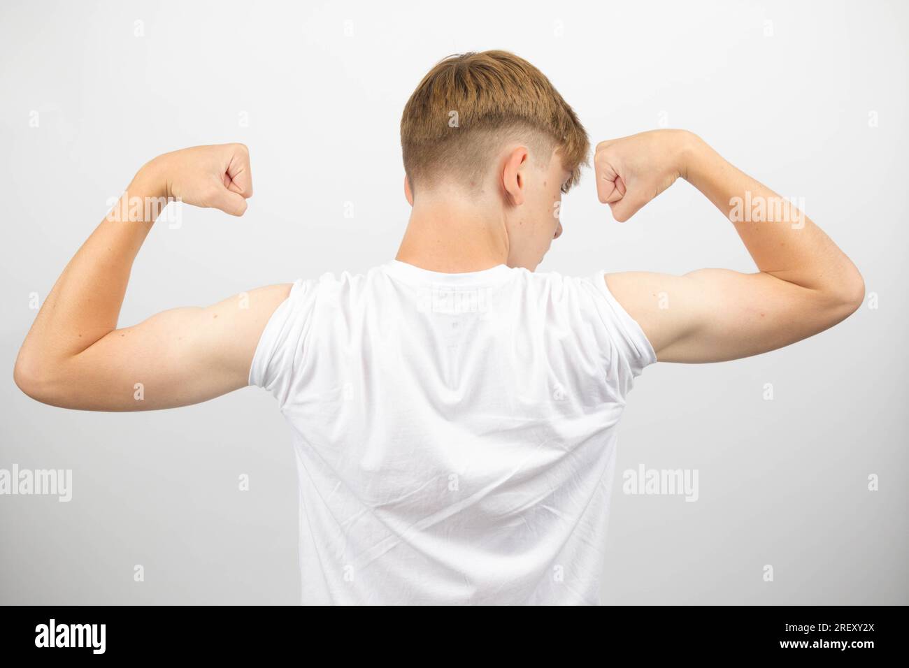 Teenage boy flexing both his arms Stock Photo - Alamy