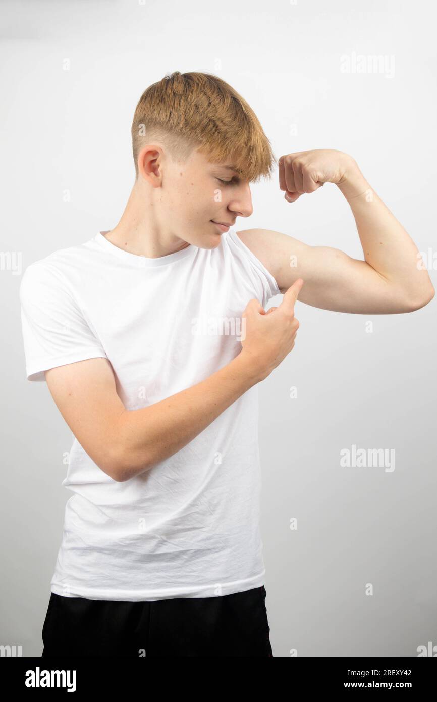 Portrait of a 14 year old caucasian teenage boy flexing his bicep and ...