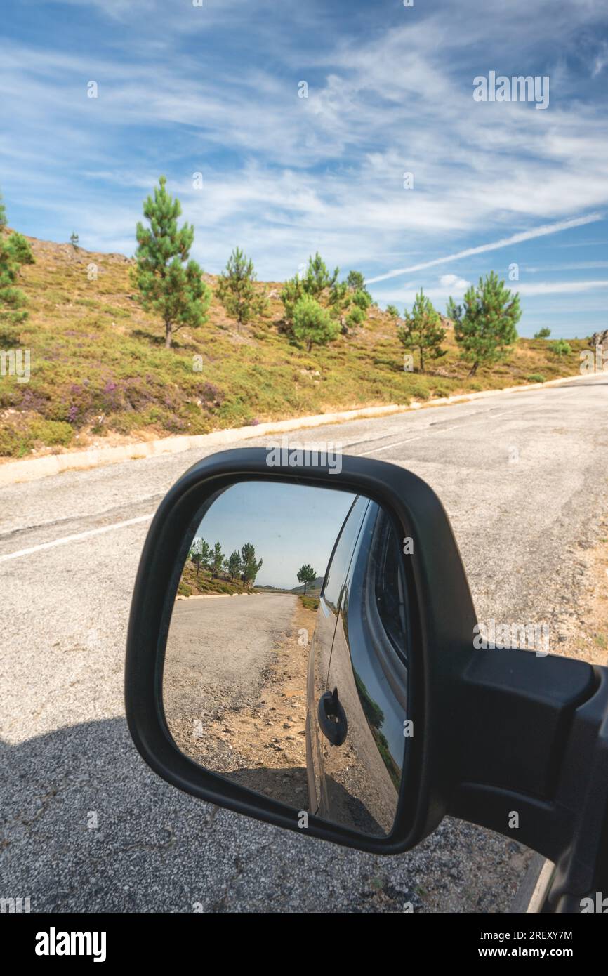 Car parked on the side of a countryroad, with the road in the mirrow ...