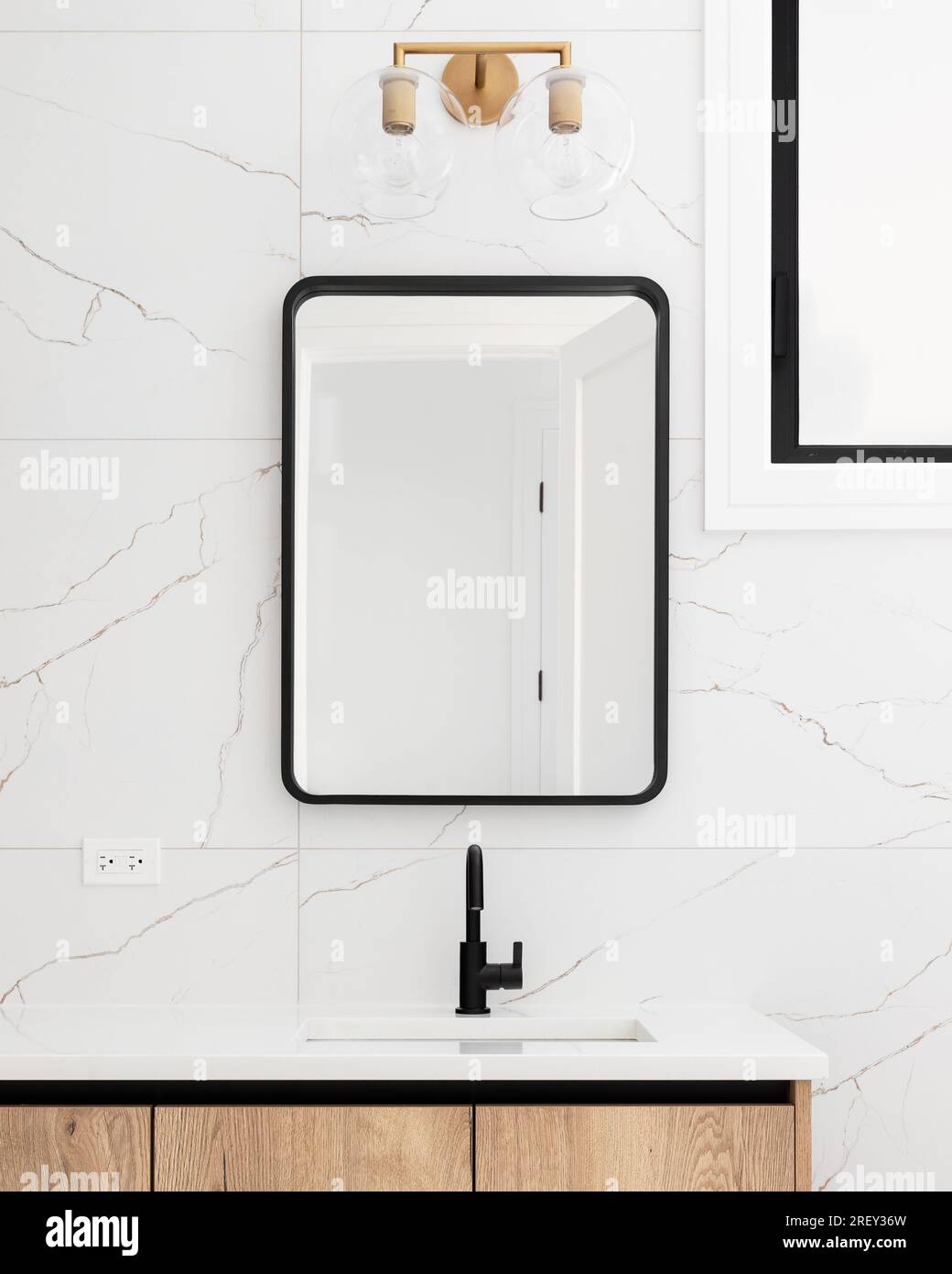 A bathroom detail with a wood cabinet, marble tiled wall, and gold ...
