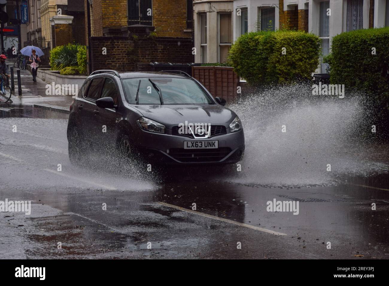 London, England, UK. 30th July, 2023. A car splashes through a large ...