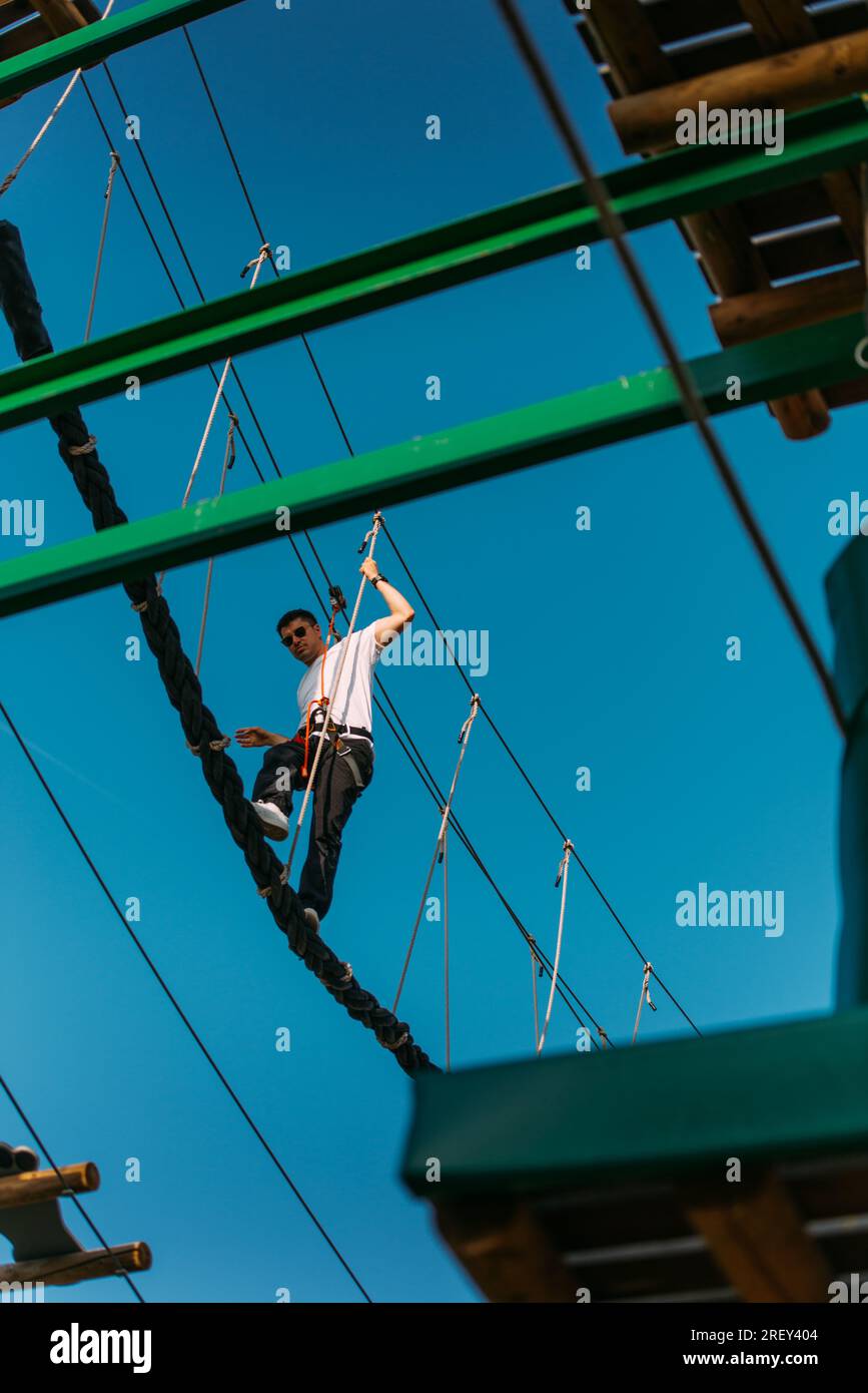 Handsome trained man going through the single rope bridge in the ...