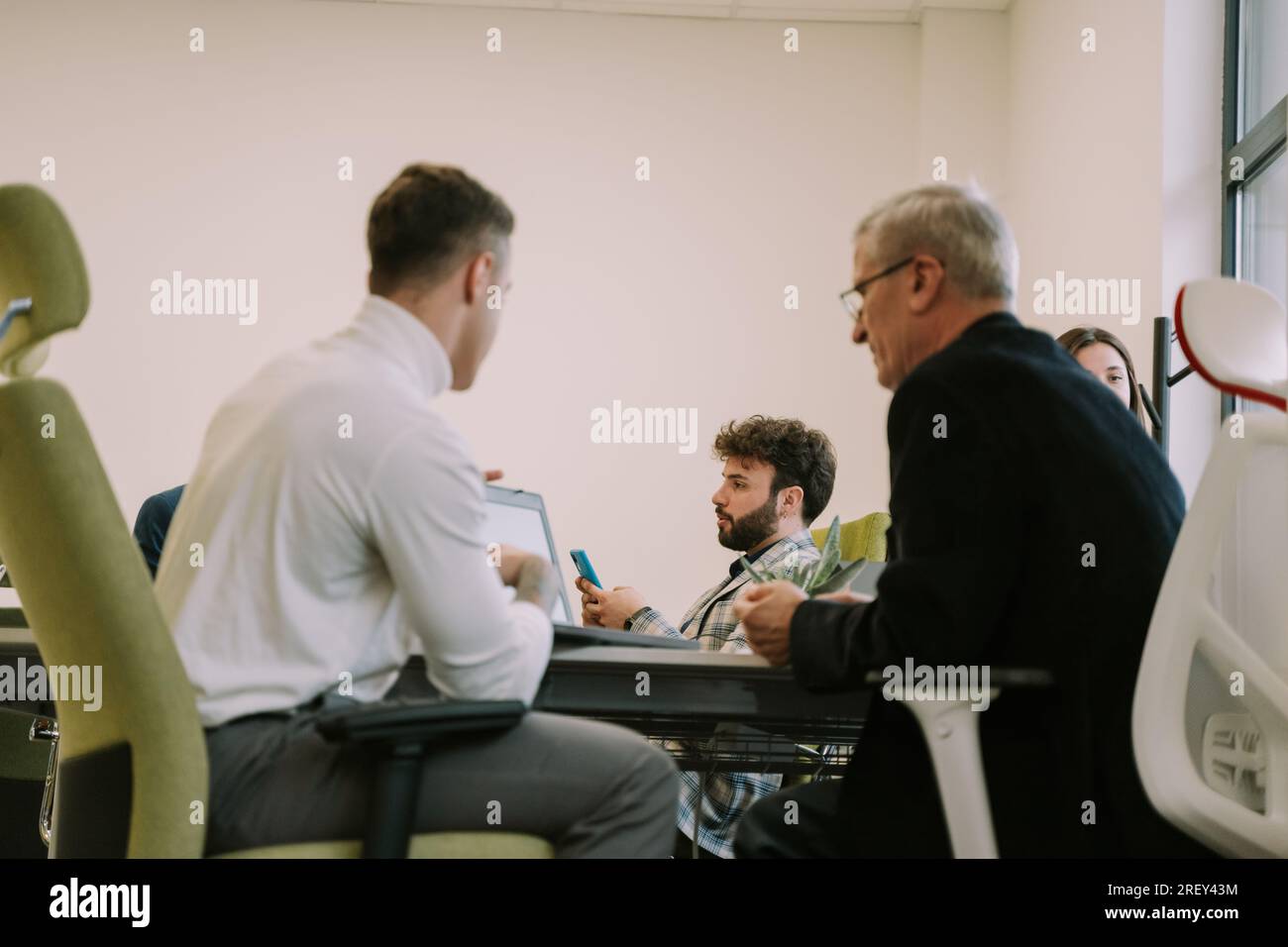 Senior male guiding and tutoring the new young employee at the office ...