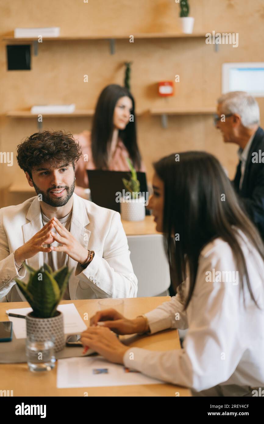 An attractive businessman listening to his female coworker explaining ...