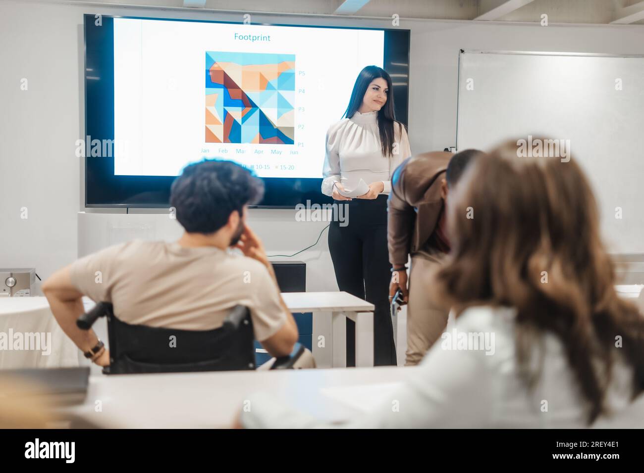 Stunning, 30s, brunette businesswoman doing presentation at meeting with creative multiracial ...