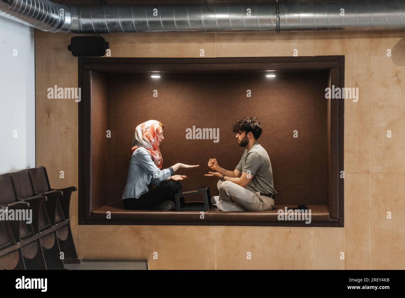 Man and woman comfortably sitting down in a recessed sofa area and ...