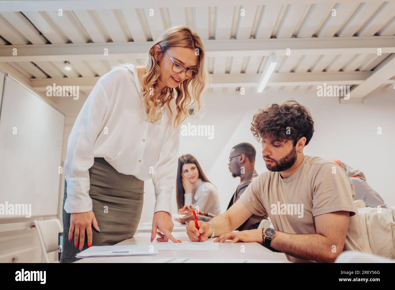 Male student solving exam question while his coach is following and ...