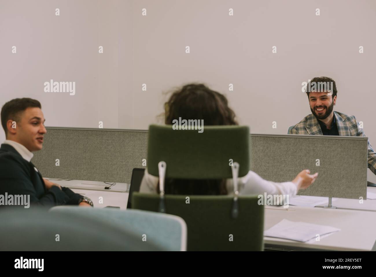 Three amazing colleagues talking while sitting at the office desk of ...