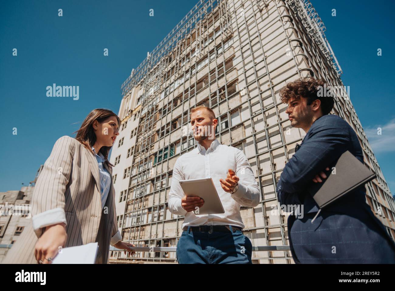 Architects in formal wear working outdoors. Male person explaining ...
