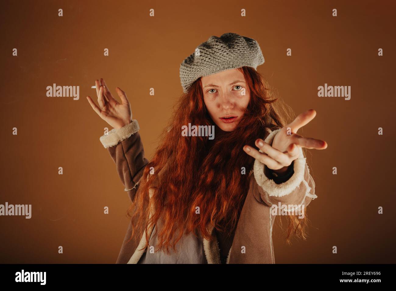 Ginger girl is moving with her hands and holding a cigarette while ...
