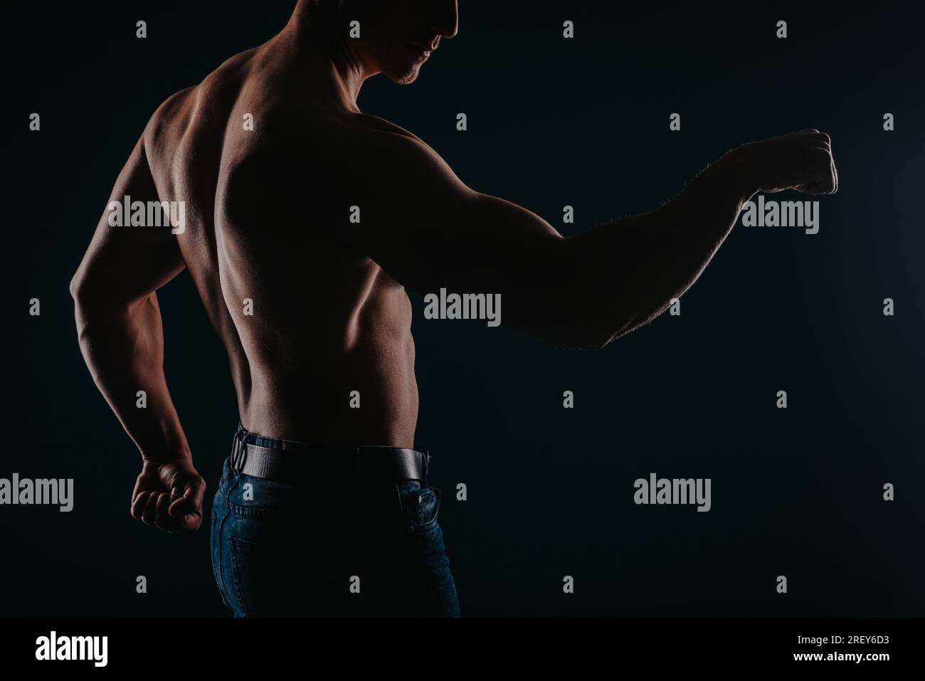 Muscular and good-looking man standing in front of a dark background ...