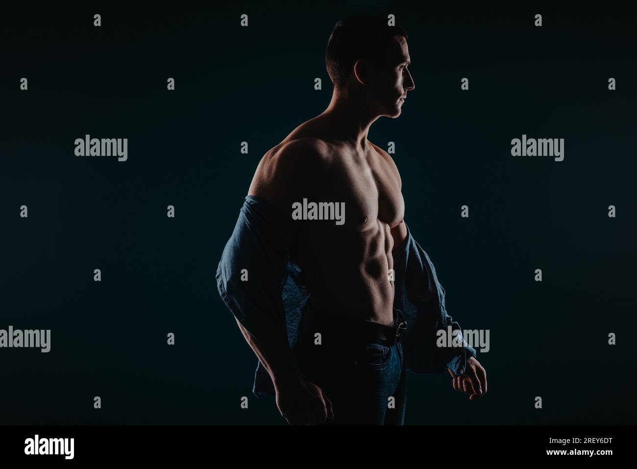 Well-built and attractive man standing in a dark room and flexing his ...