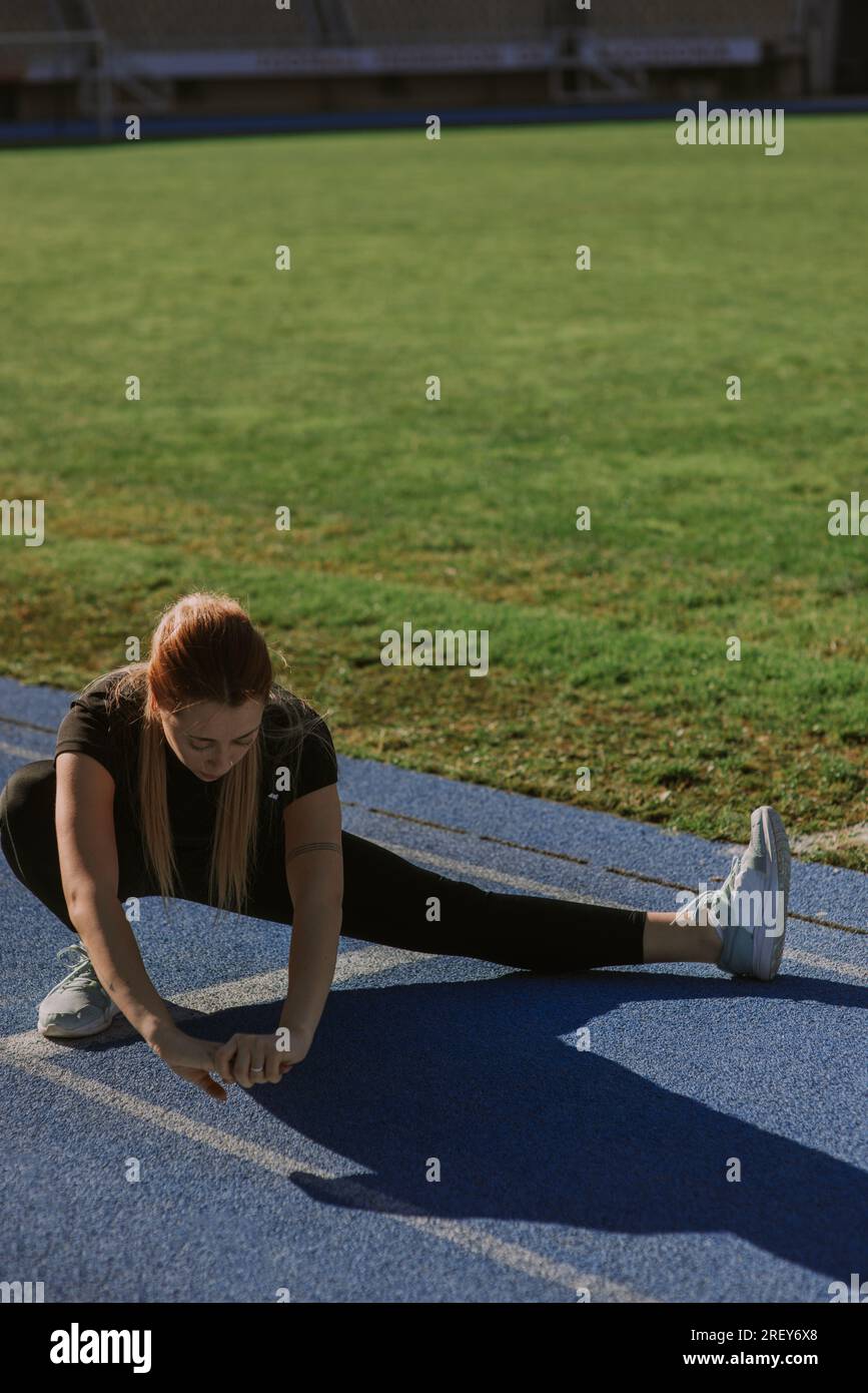 Lovely girl is exercising at the stadium, early in the morning. She is ...