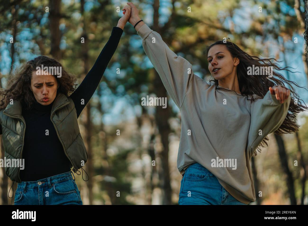 Front view shot of two lovely girls dancing while walking. They are ...