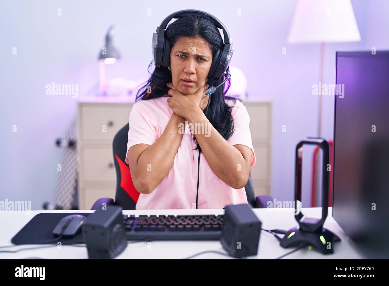 Mature hispanic woman playing video games at home shouting and ...