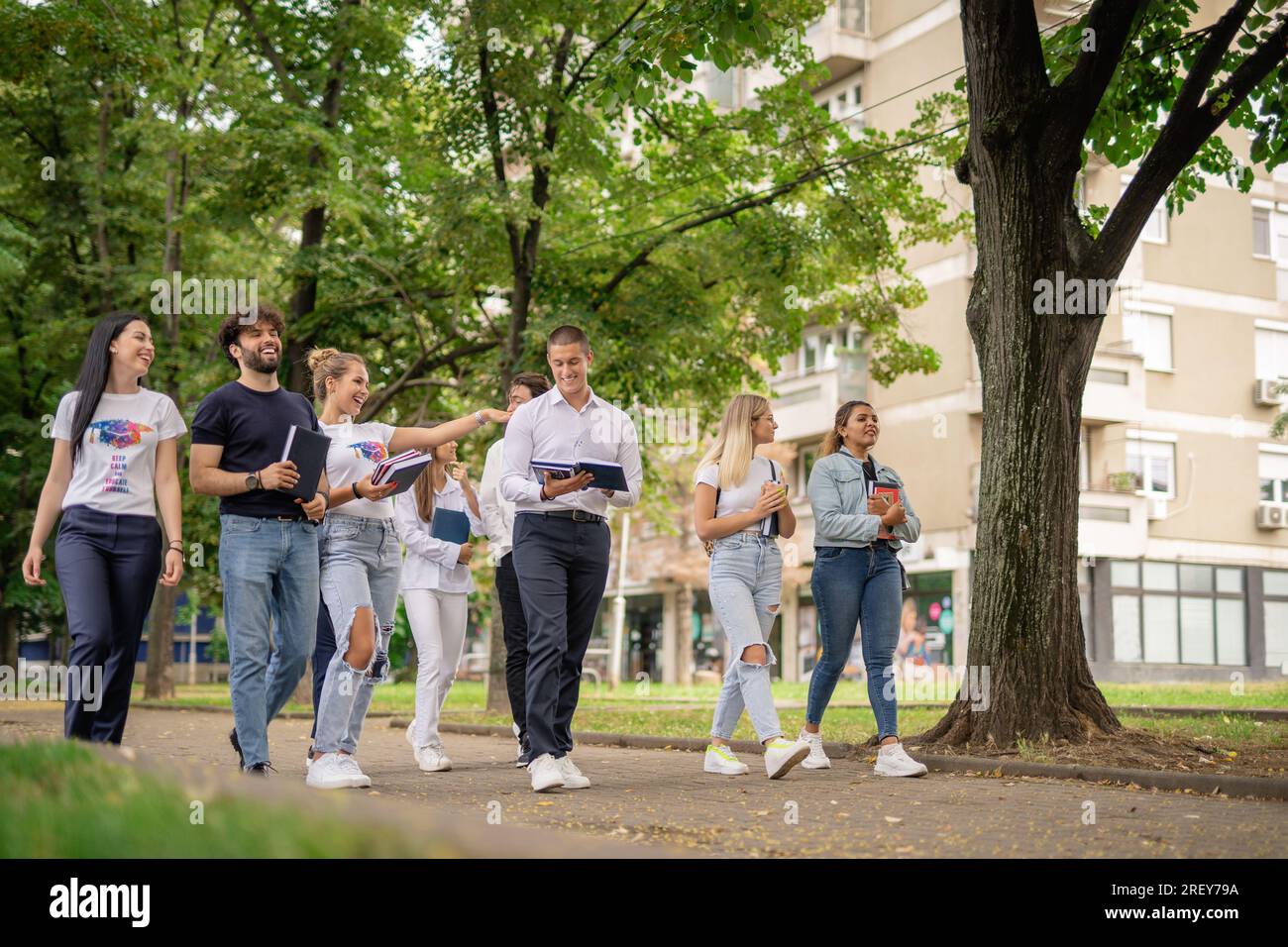 Young college students all together walking towards their school with ...