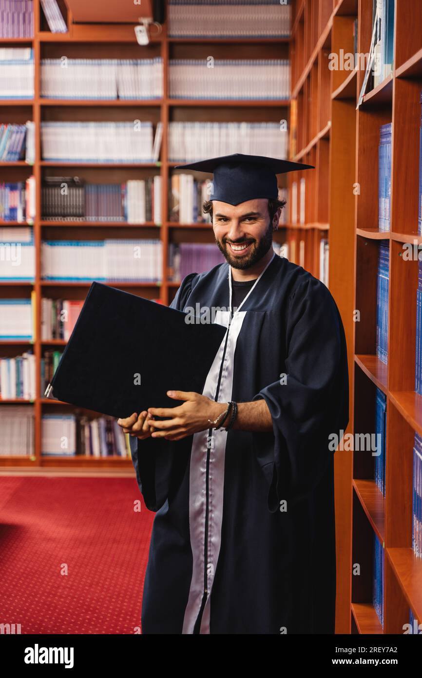 Excited graduate wearing a cap and gown happy to receive his bachelor's ...