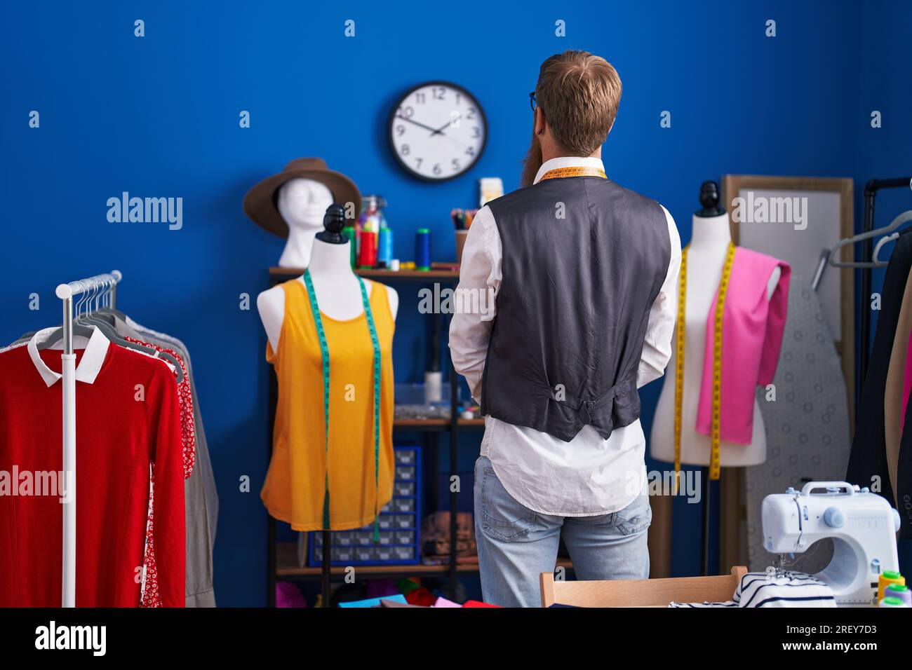 Young redhead man tailor standing on back view at clothing factory ...